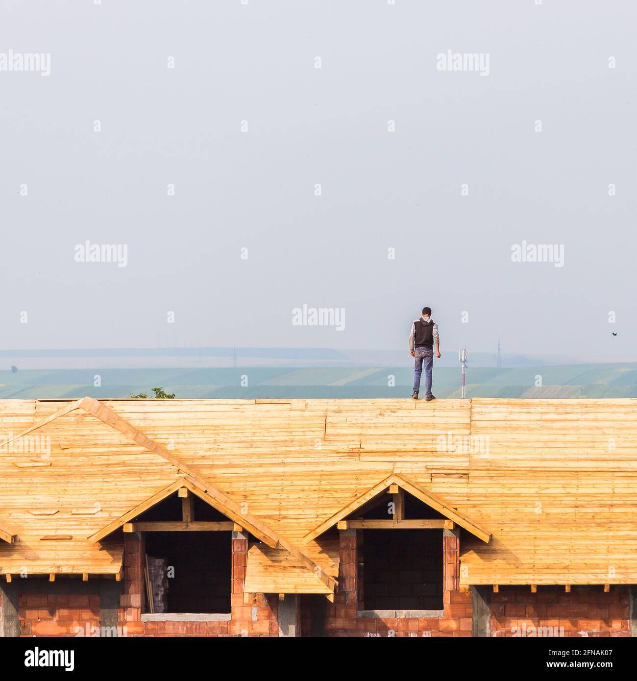 Man standing on top of a wooden building under a clear sky Stock Photo ...