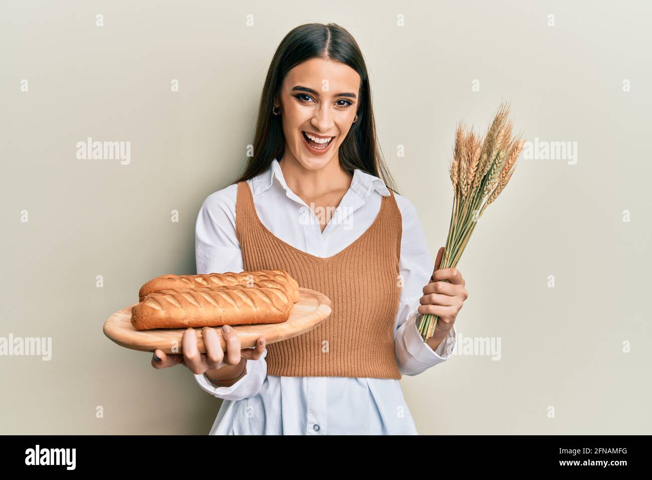 Beautiful brunette young woman holding homemade bread and spike wheat ...