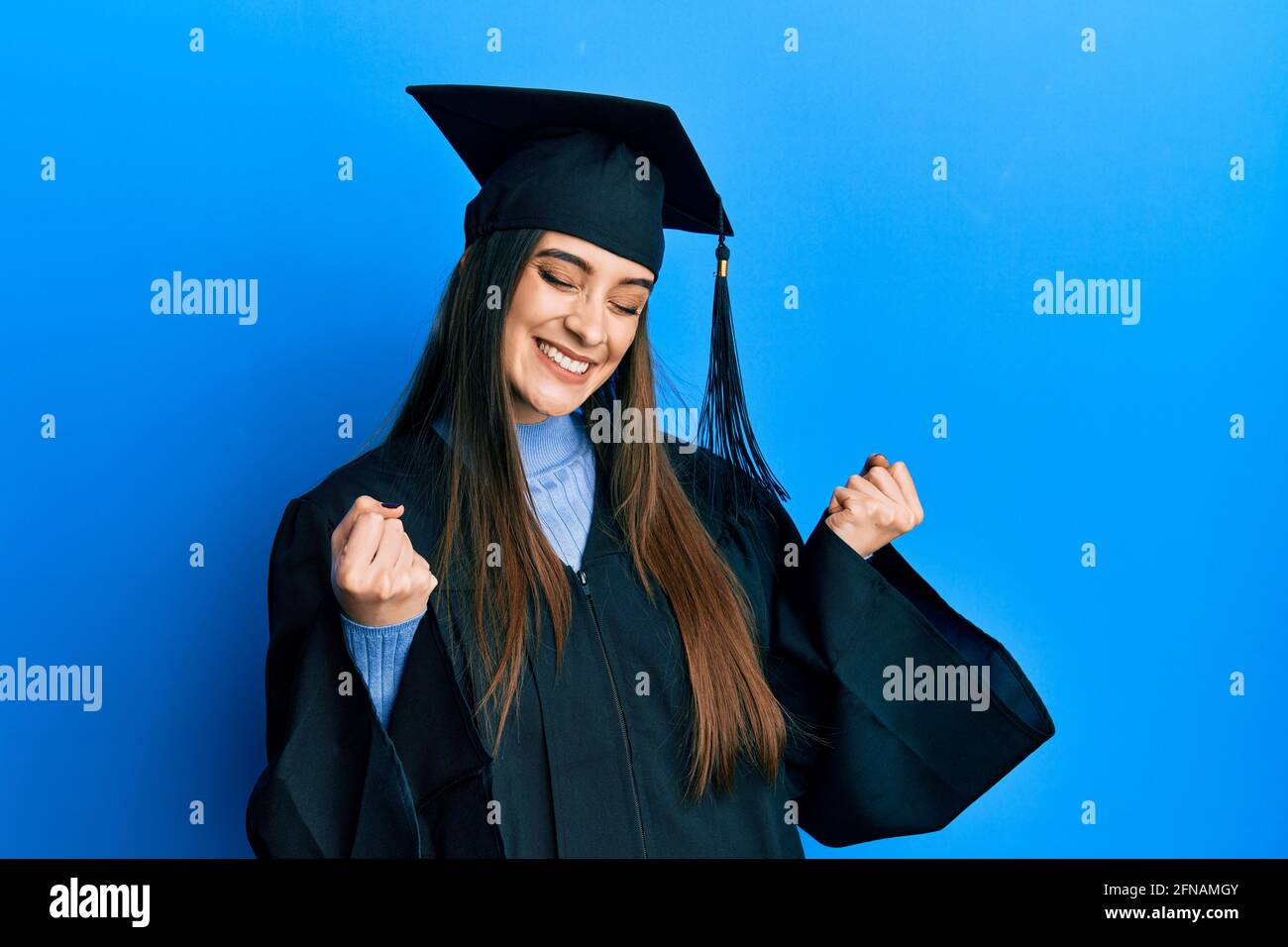 Beautiful brunette young woman wearing graduation cap and ceremony robe ...