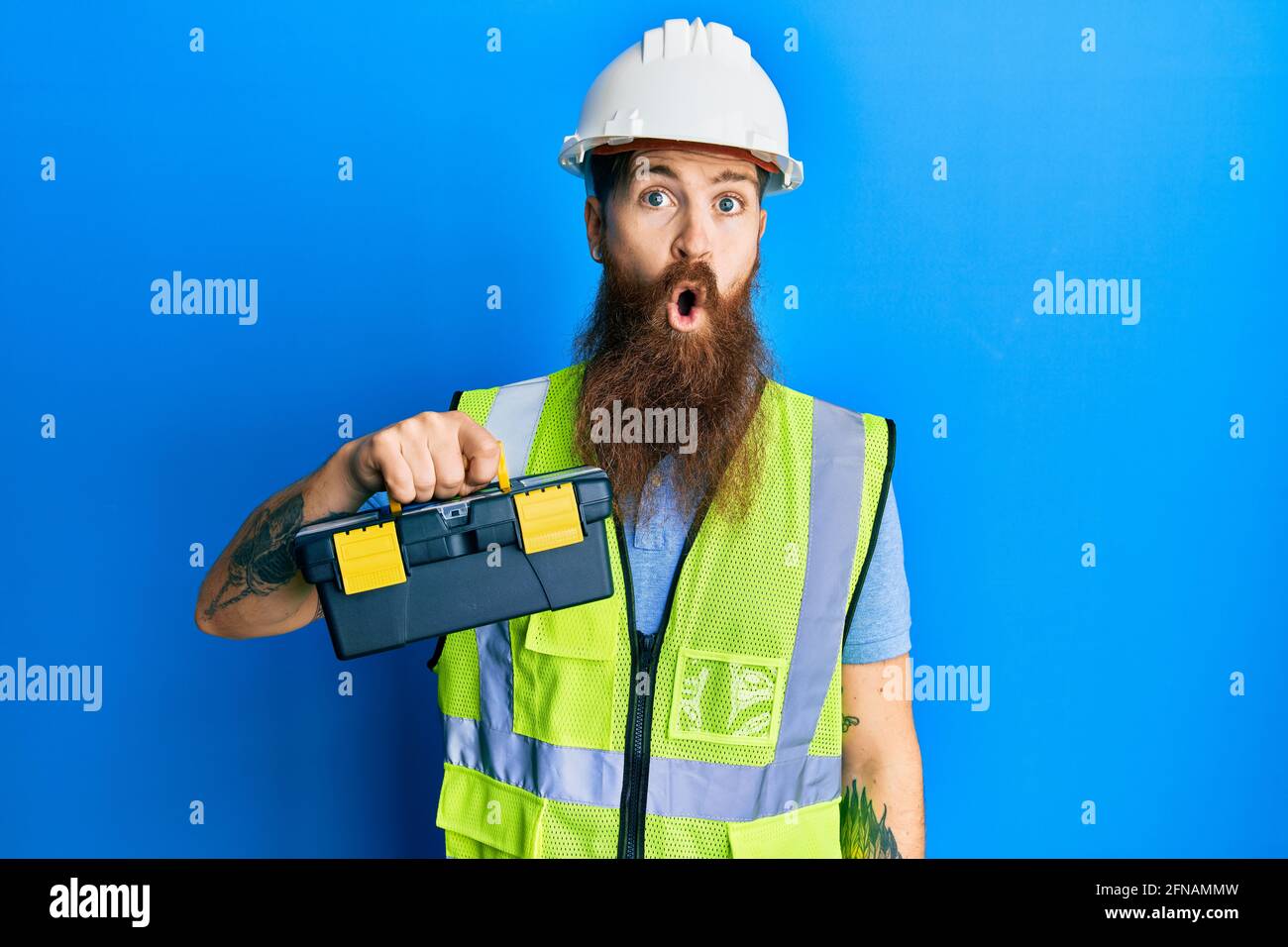 Redhead man with long beard wearing safety helmet and reflective jacket ...