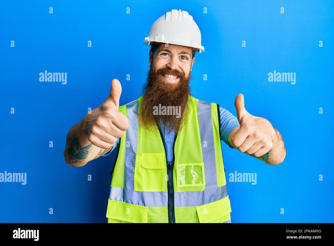 Redhead man with long beard wearing safety helmet and reflective jacket ...