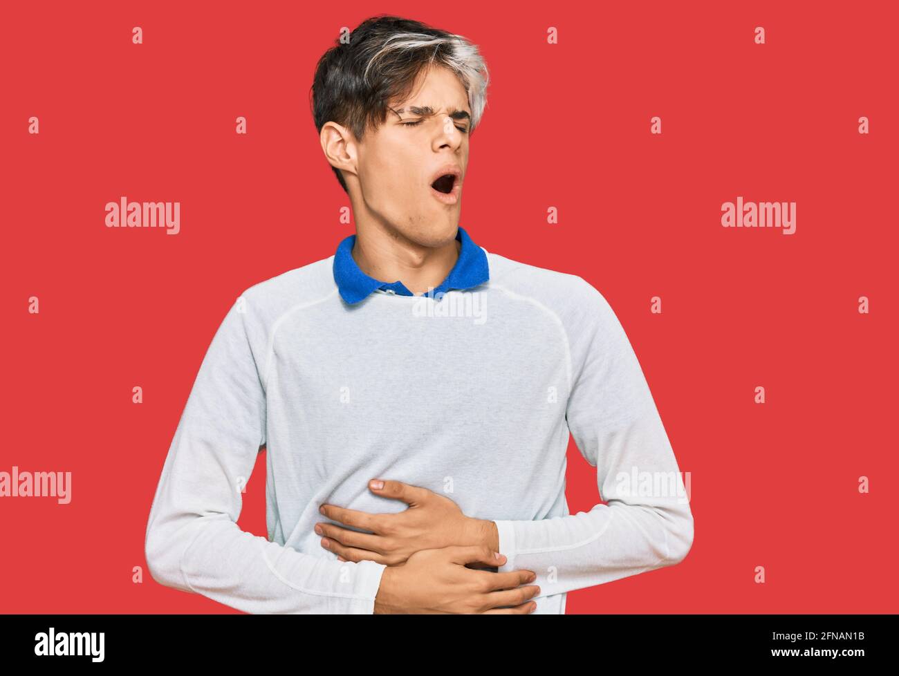 Young hispanic man wearing casual clothes with hand on stomach because ...