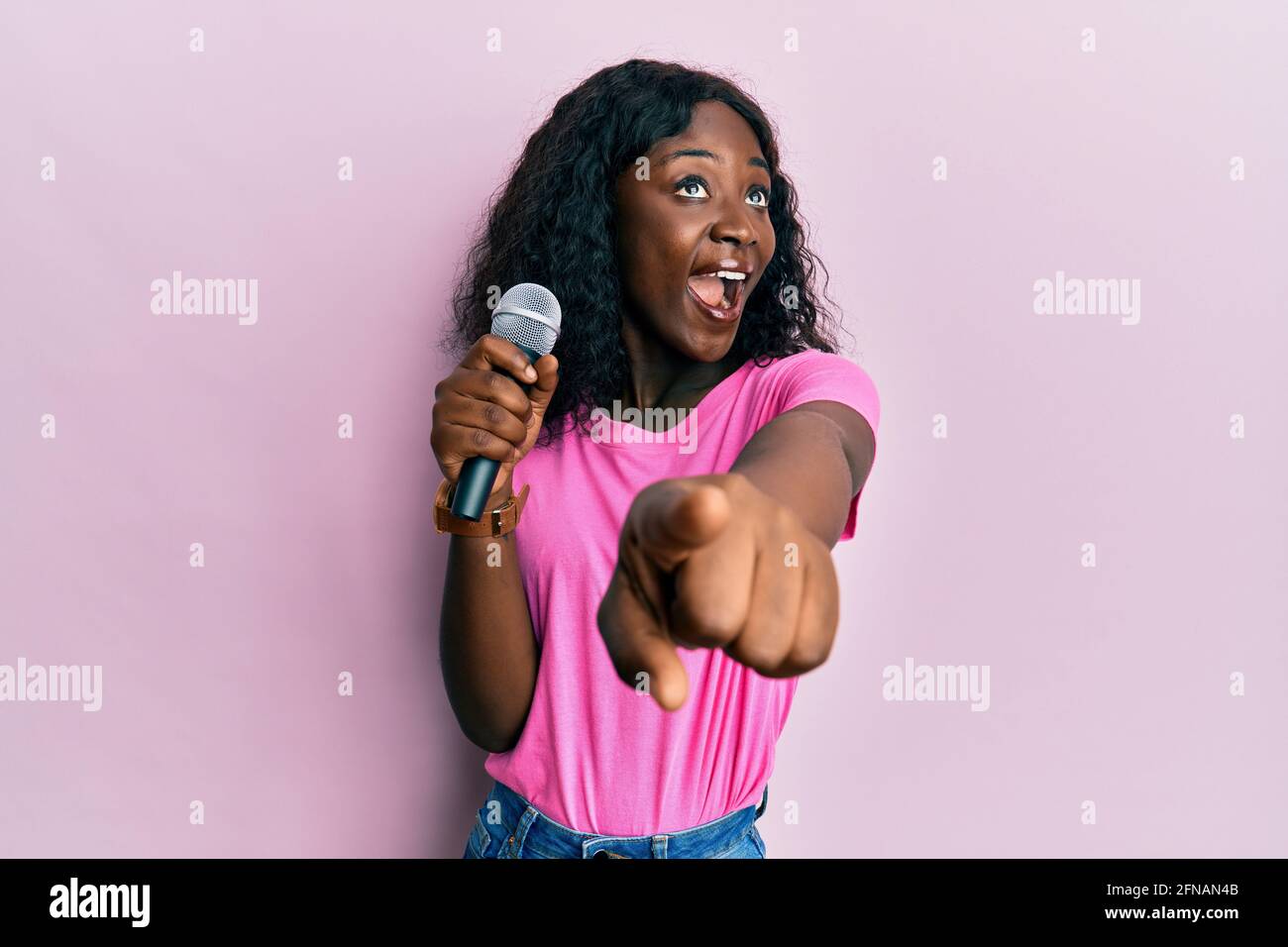 Beautiful african young woman singing song using microphone pointing to ...