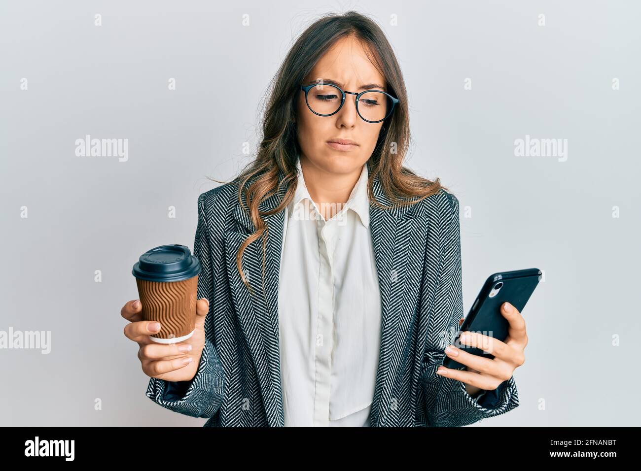 Young brunette woman using smartphone and drinking a cup of coffee ...