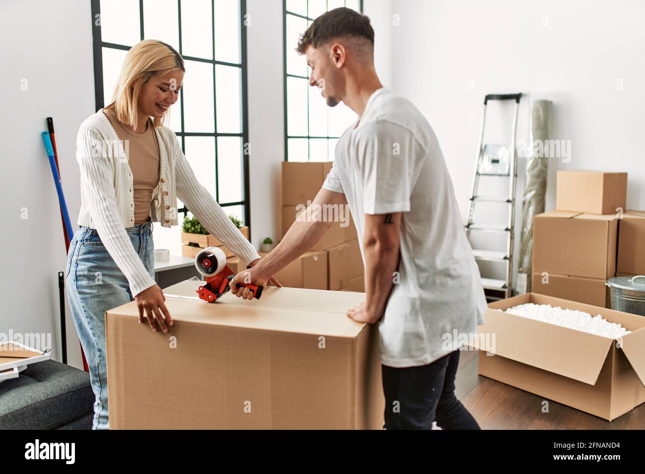 Young caucasian couple smiling happy closing box using packing tape at ...