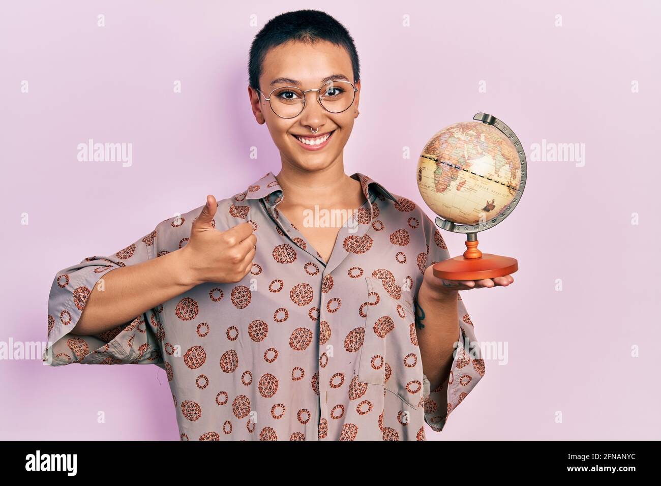 Beautiful hispanic woman with short hair holding small world ball ...