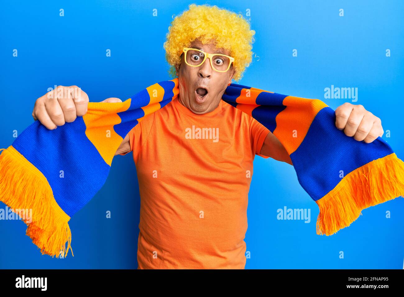 Senior hispanic man football hooligan cheering game in shock face ...