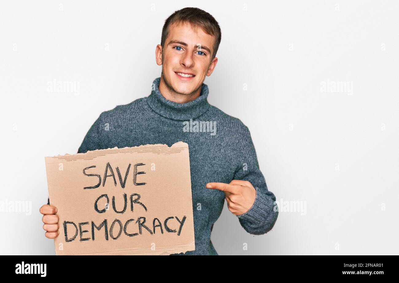 Young blond man holding save our democracy protest banner smiling happy ...
