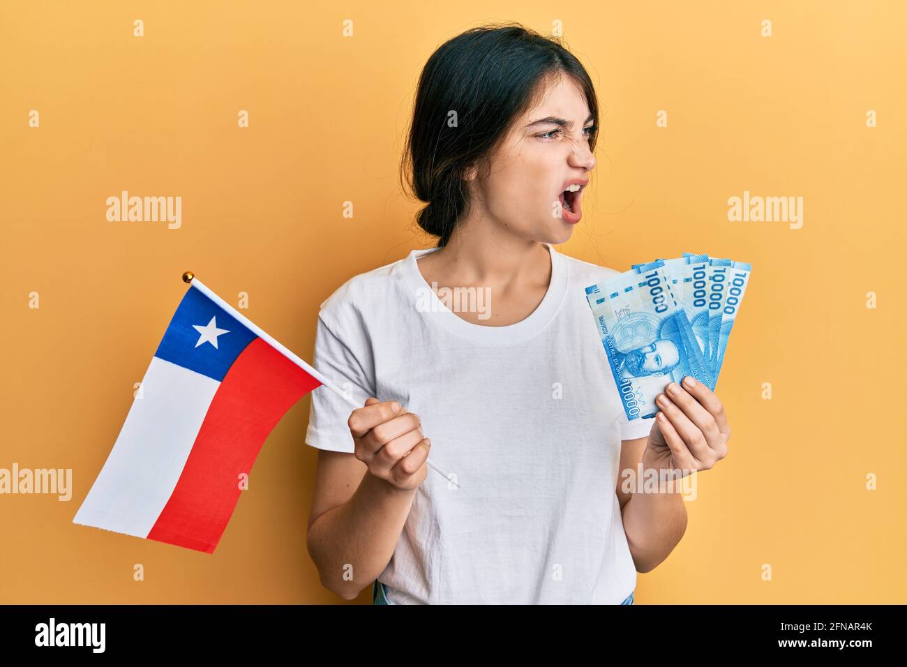 Young caucasian woman holding chile flag and chilean pesos banknotes ...