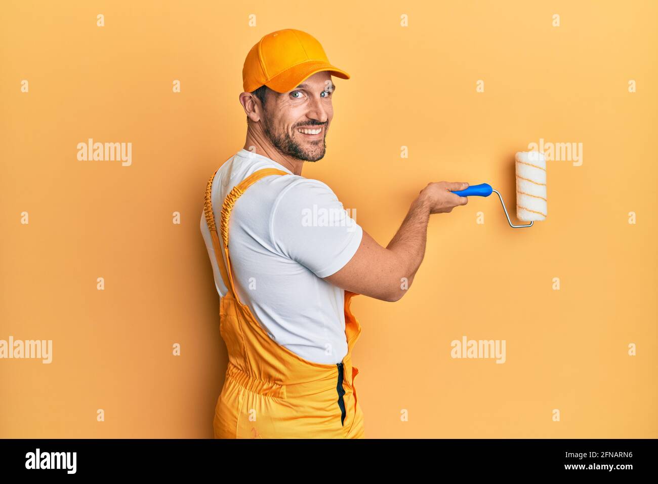 Young caucasian painter smiling happy painting wall using roller Stock ...