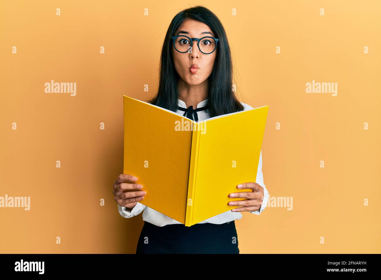 Beautiful asian young woman reading a book wearing glasses making fish ...