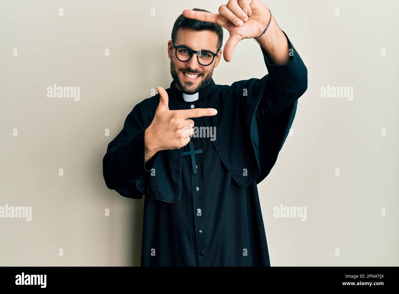 Young hispanic man wearing priest uniform standing over white ...