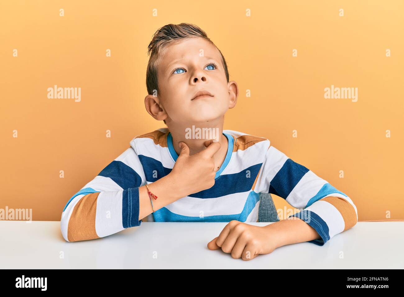 Adorable caucasian kid wearing casual clothes sitting on the table ...
