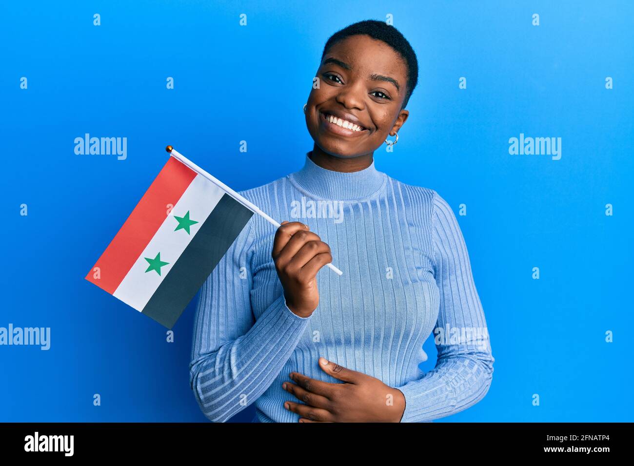 Young african american woman holding syria flag looking positive and ...