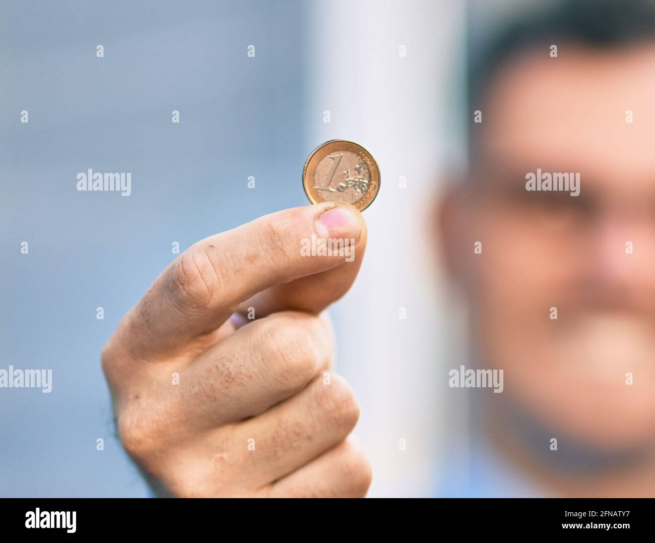 Young hispanic businessman smiling happy holding 1 euro coin at the ...