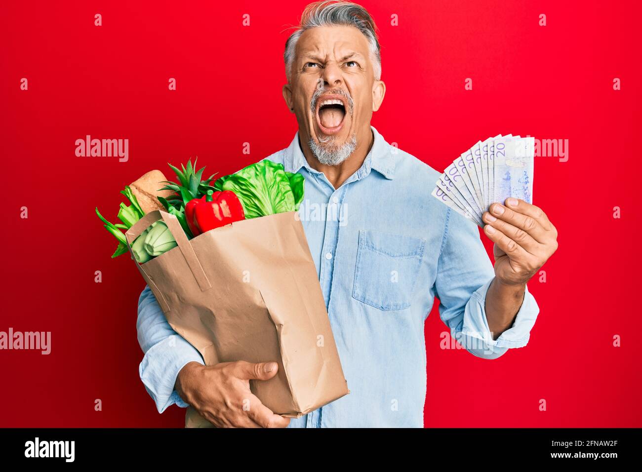 Middle age grey-haired man holding groceries and swedish krona ...