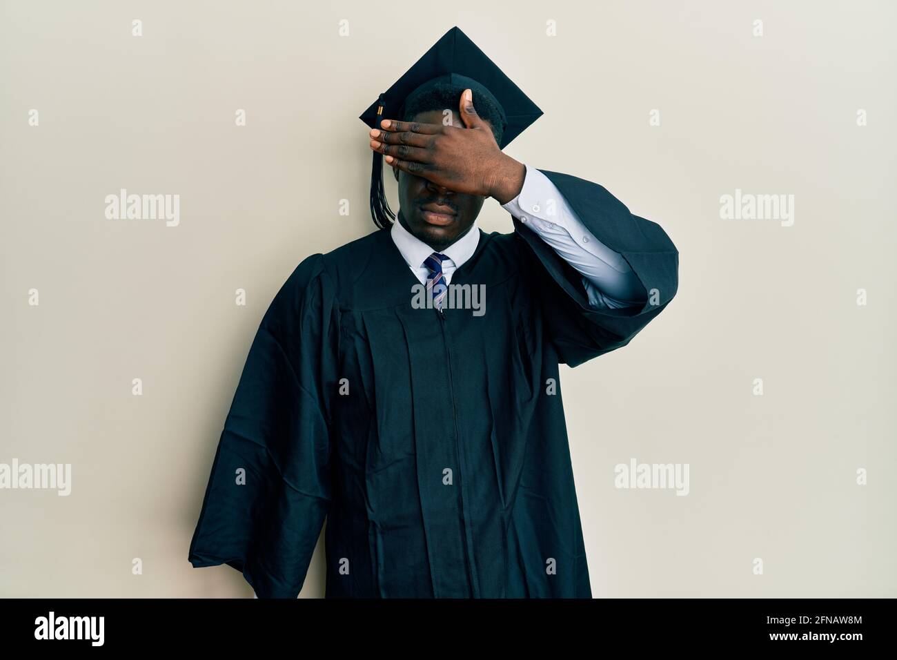Handsome black man wearing graduation cap and ceremony robe covering ...
