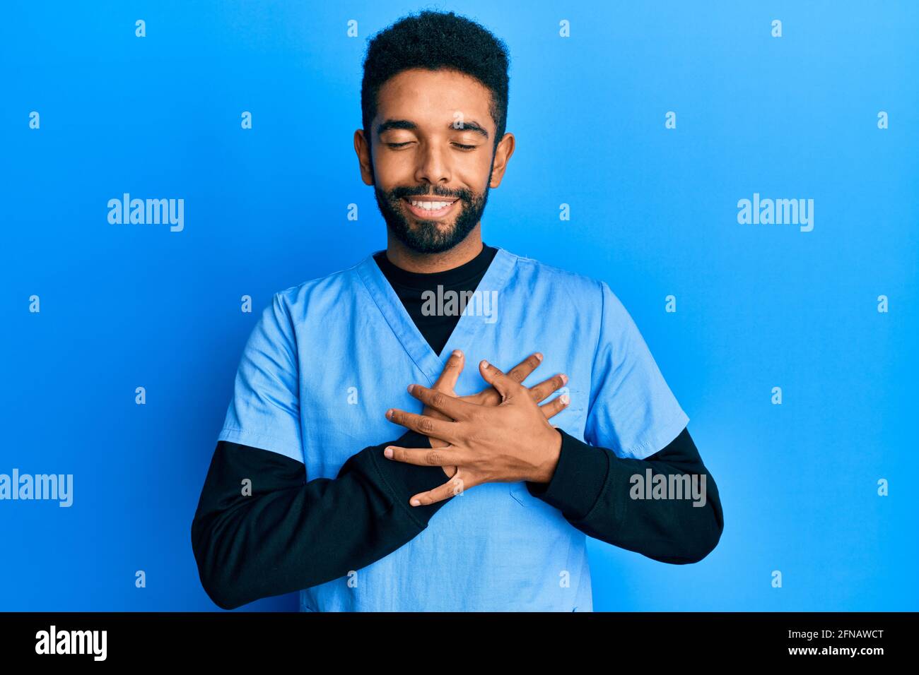 Handsome hispanic man with beard wearing blue male nurse uniform ...