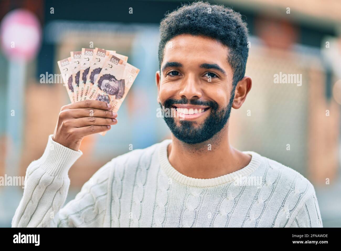 Young african american man smiling happy holding mexican 500 pesos ...
