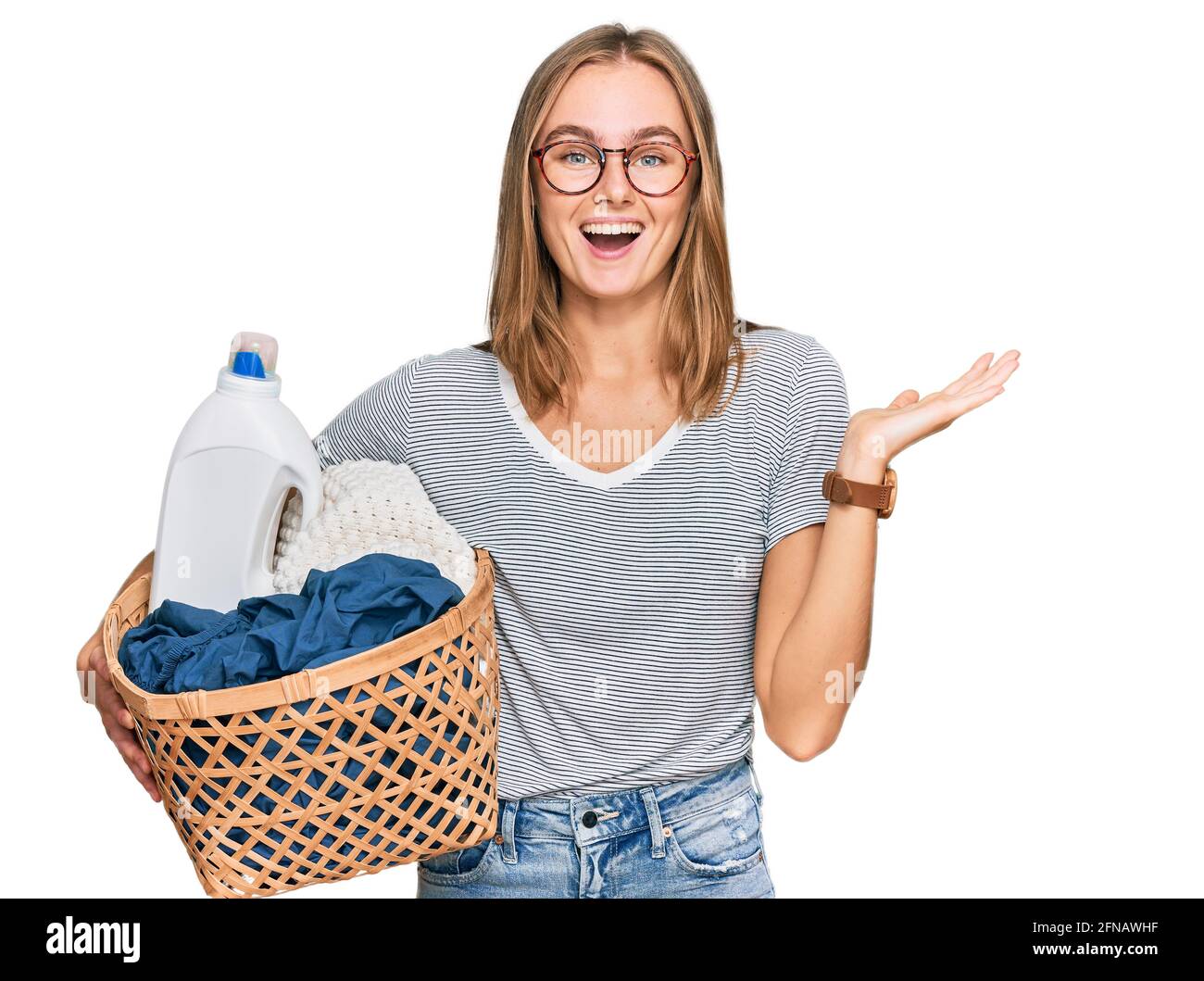 Beautiful blonde woman holding laundry basket and detergent bottle ...