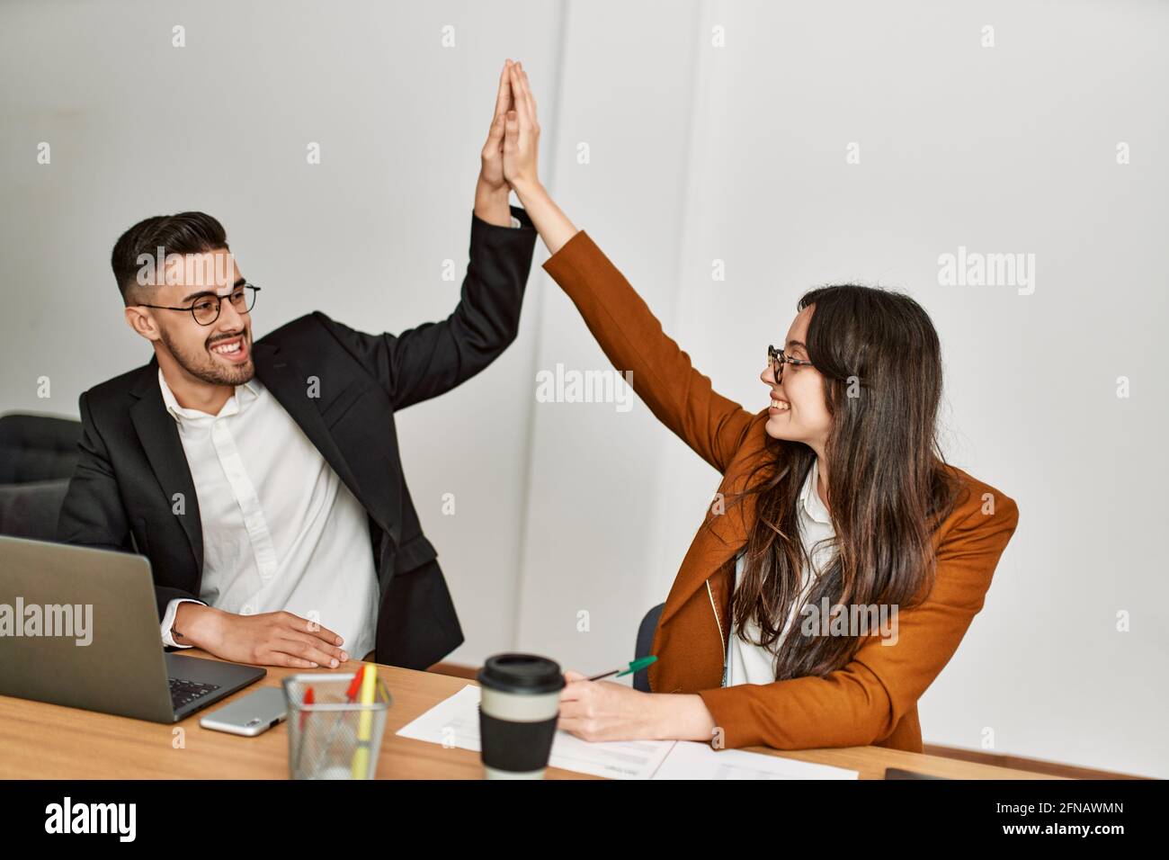 Two business executives raised up hands hitting five at the office ...