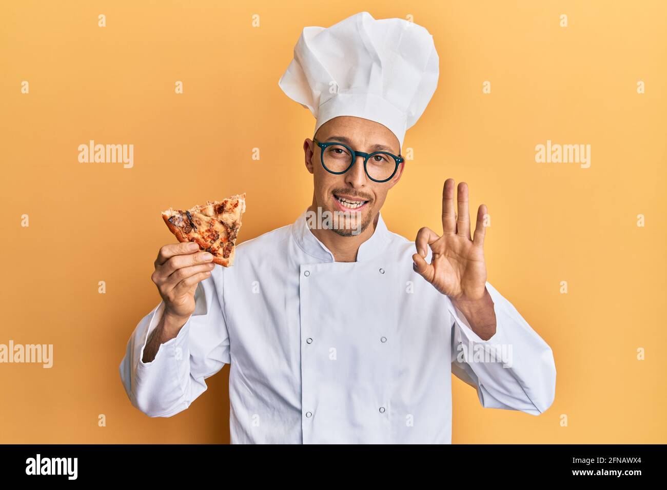 Bald man with beard wearing professional cook apron holding italian ...