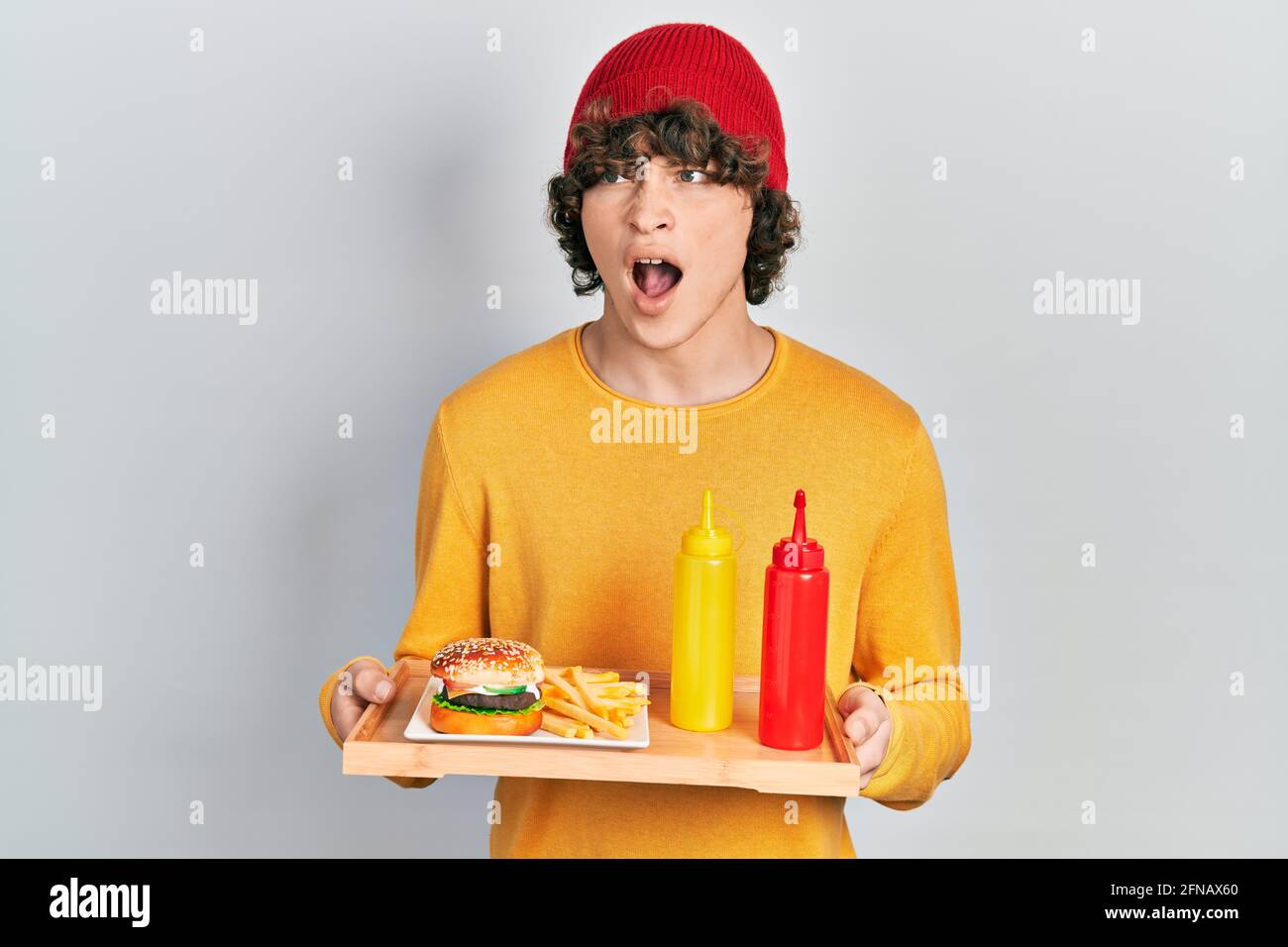 Handsome young man eating a tasty classic burger with ketchup and ...