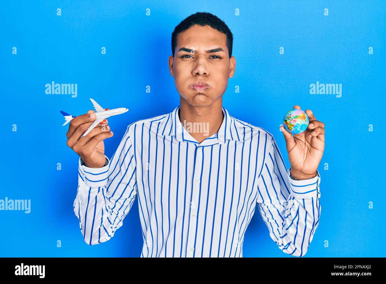 Young african american guy holding paper plane and world ball puffing ...