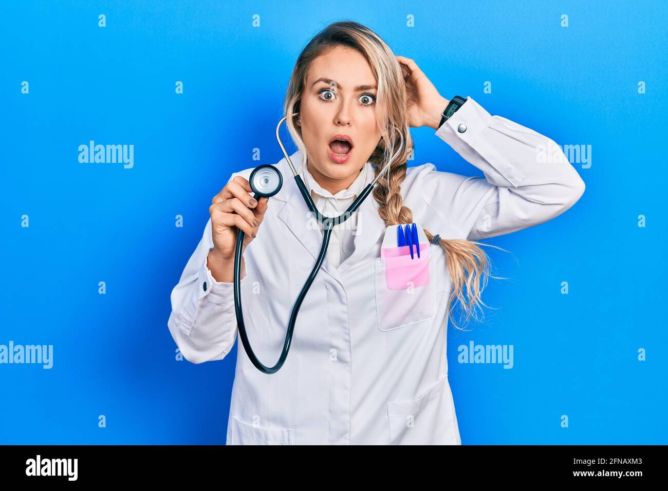 Beautiful young blonde doctor woman holding stethoscope crazy and ...