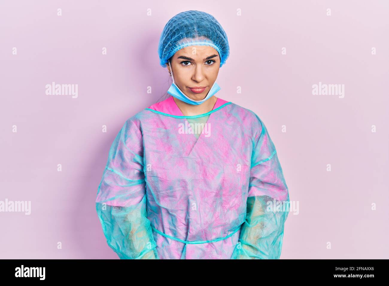 Young brunette woman wearing surgeon uniform and medical mask depressed ...