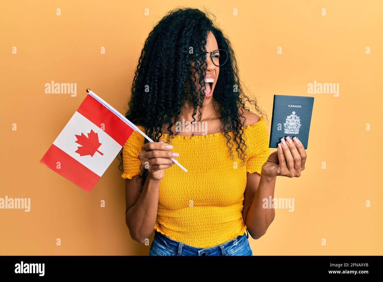 Middle age african american woman holding canada flag and passport ...