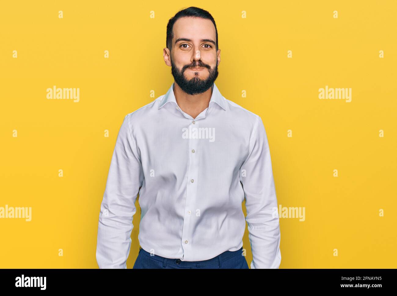 Young man with beard wearing business shirt puffing cheeks with funny ...