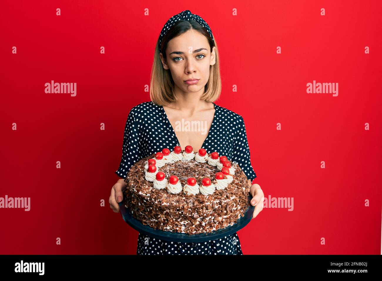 Young caucasian blonde woman holding chocolate cake depressed and worry ...