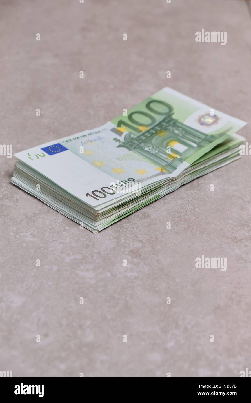A vertical shot of a stack of cash hundred Euro bills on the table ...