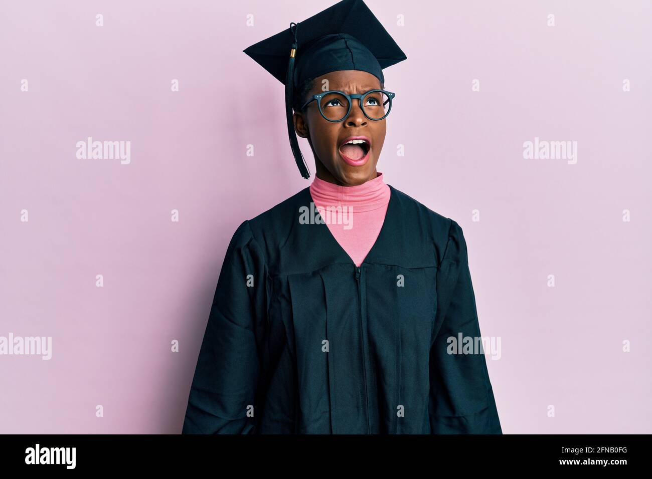 Young african american girl wearing graduation cap and ceremony robe ...
