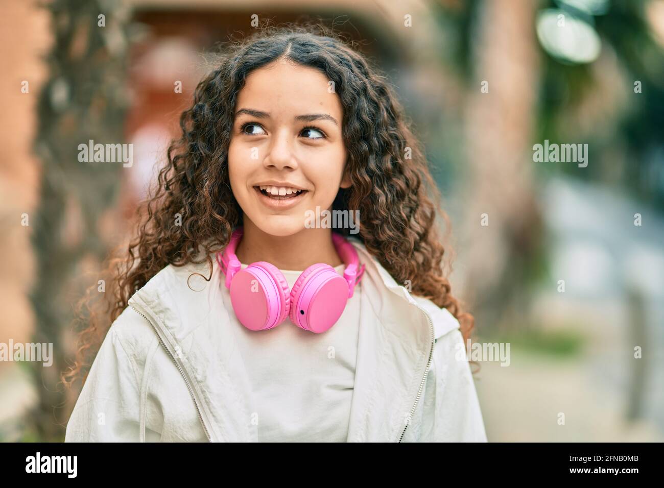 Hispanic child girl smiling happy using headphones at the city Stock ...