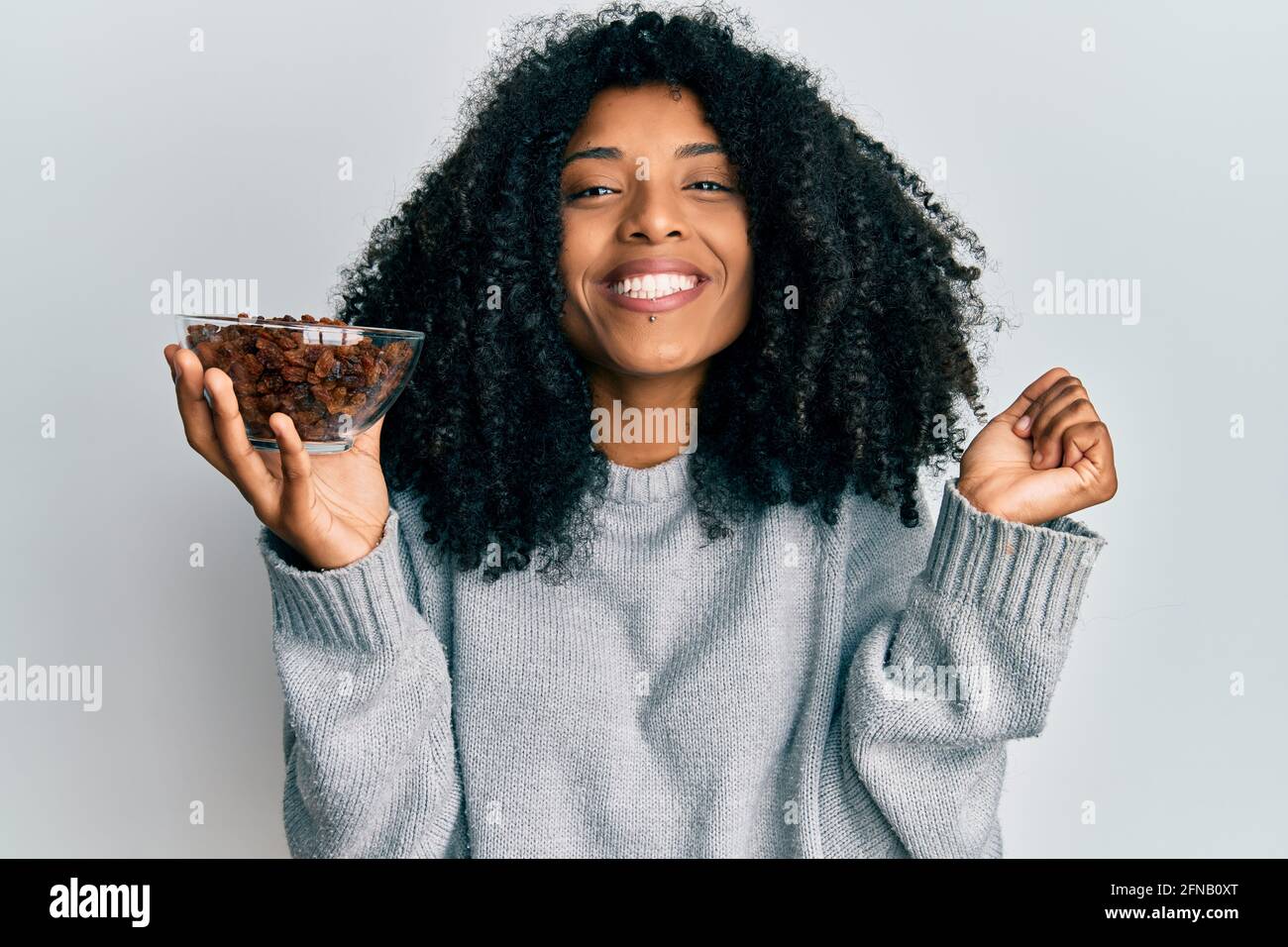 African american woman with afro hair holding raisins in bowl screaming ...