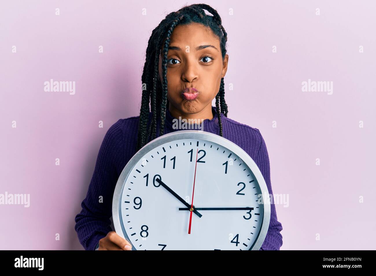 African american woman with braids holding big clock covering face ...