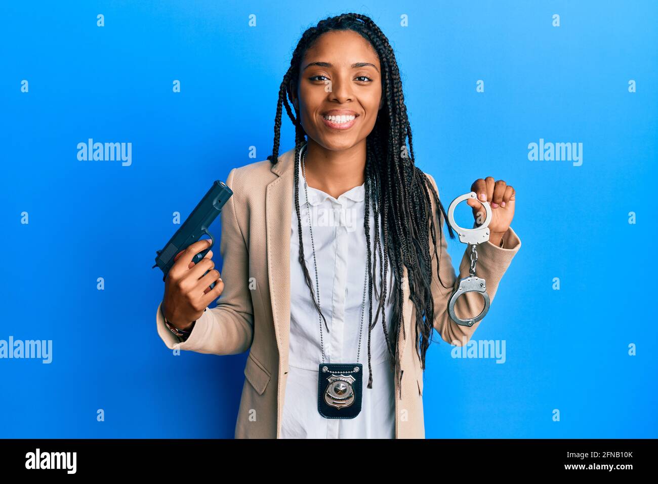 African American Police Woman Holding Gun And Handcuffs Smiling With A