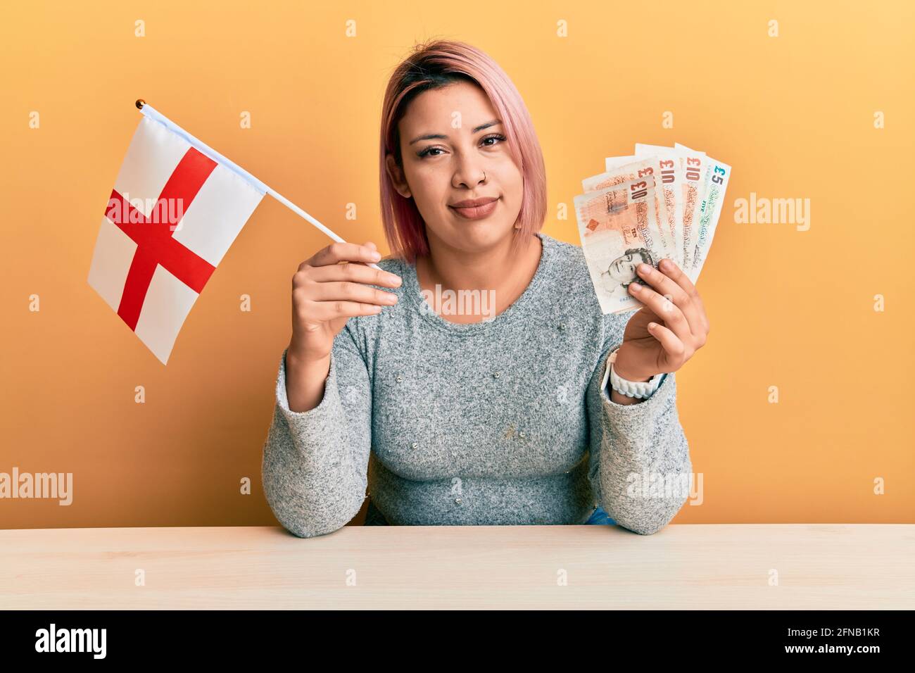 Hispanic woman with pink hair holding england flag and pounds banknotes ...