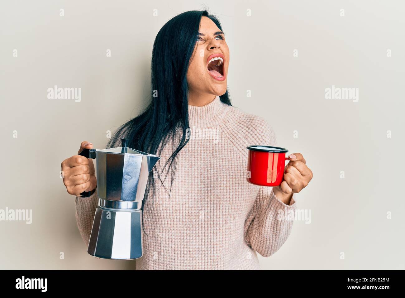 Young caucasian woman drinking italian coffee angry and mad screaming ...