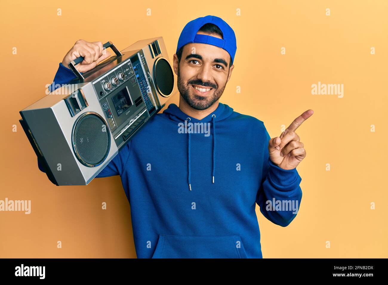 Young hispanic man holding boombox, listening to music smiling happy ...
