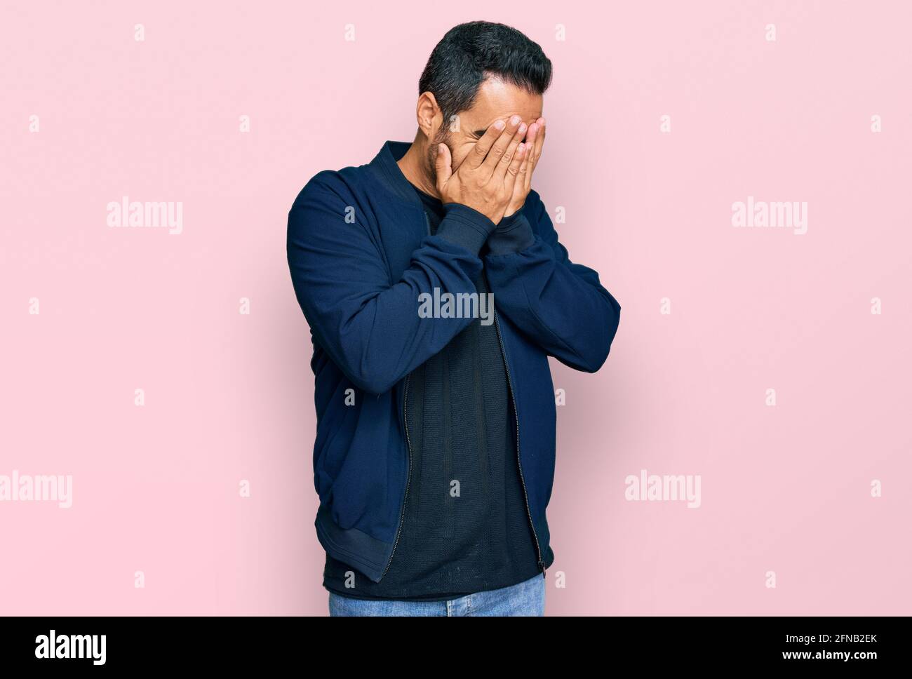 Young hispanic man wearing casual clothes with sad expression covering ...