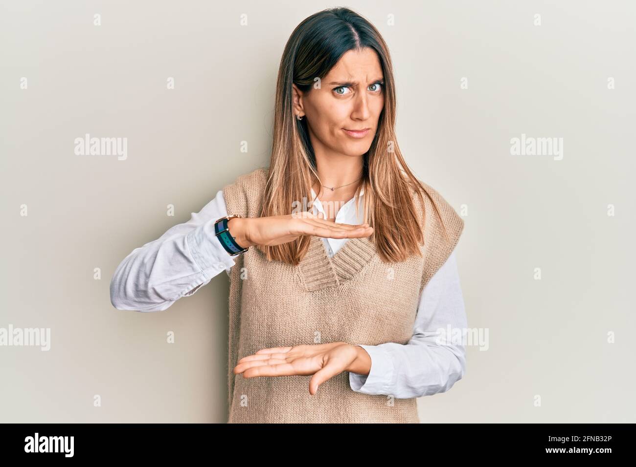 Brunette young woman doing size gesture holding invisible object ...