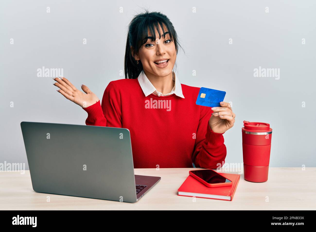 Young brunette woman with bangs working at the office using laptop and ...
