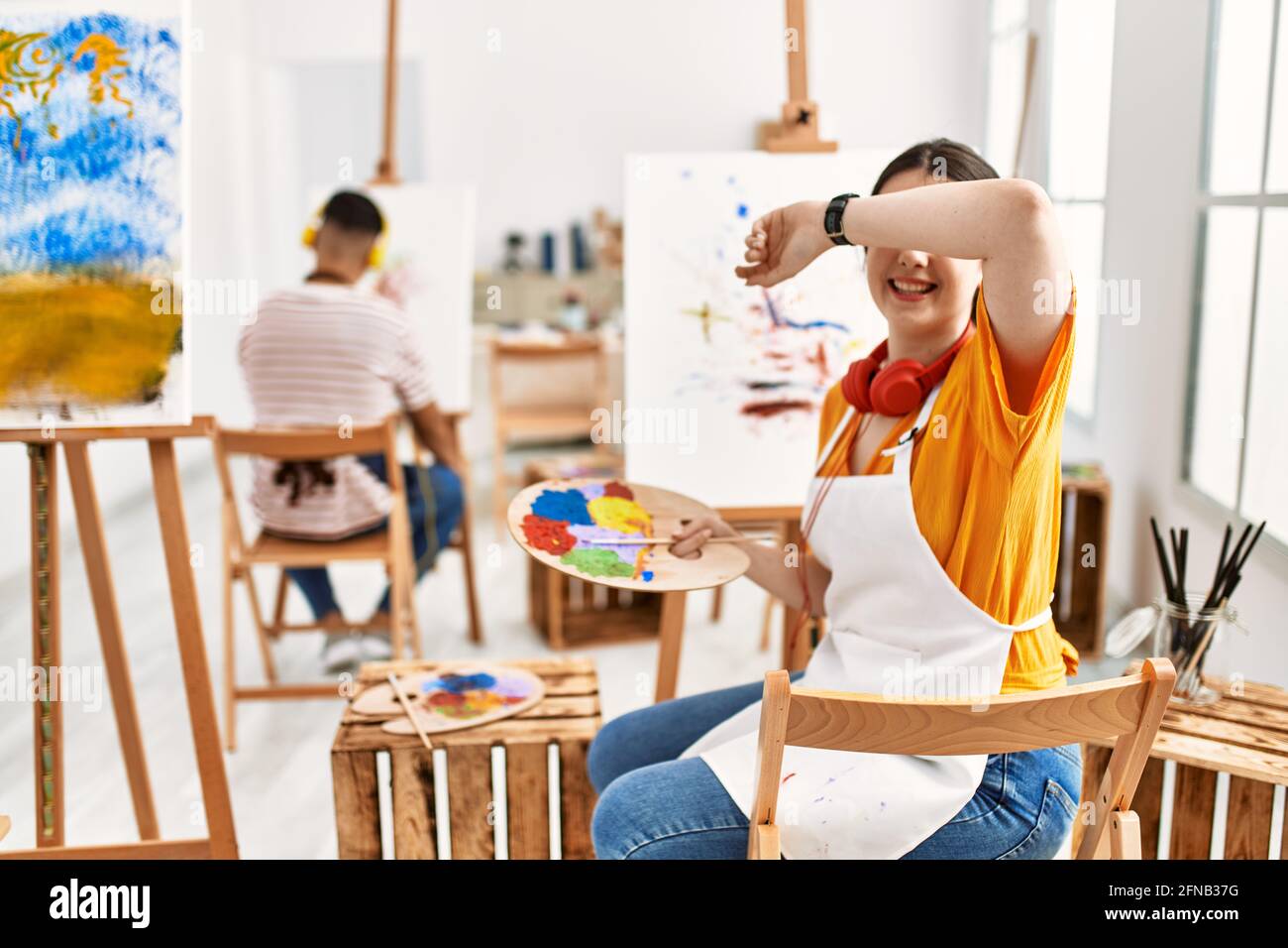 Young artist woman painting on canvas at art studio smiling cheerful ...