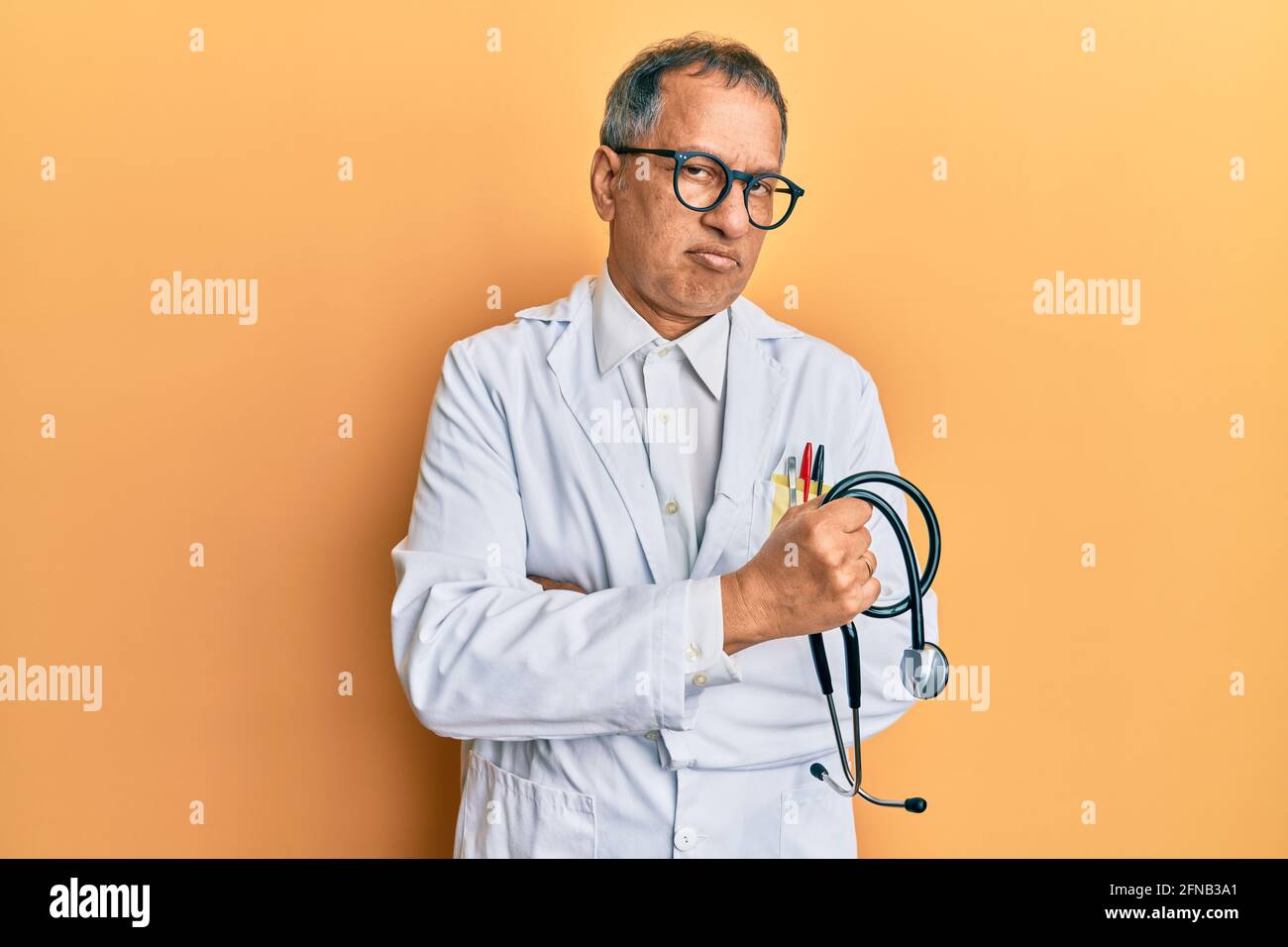 Middle age indian man wearing doctor coat holding stethoscope depressed ...