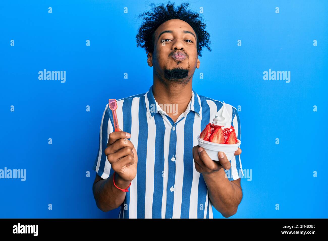 Young african american man with beard eating strawberry ice cream ...