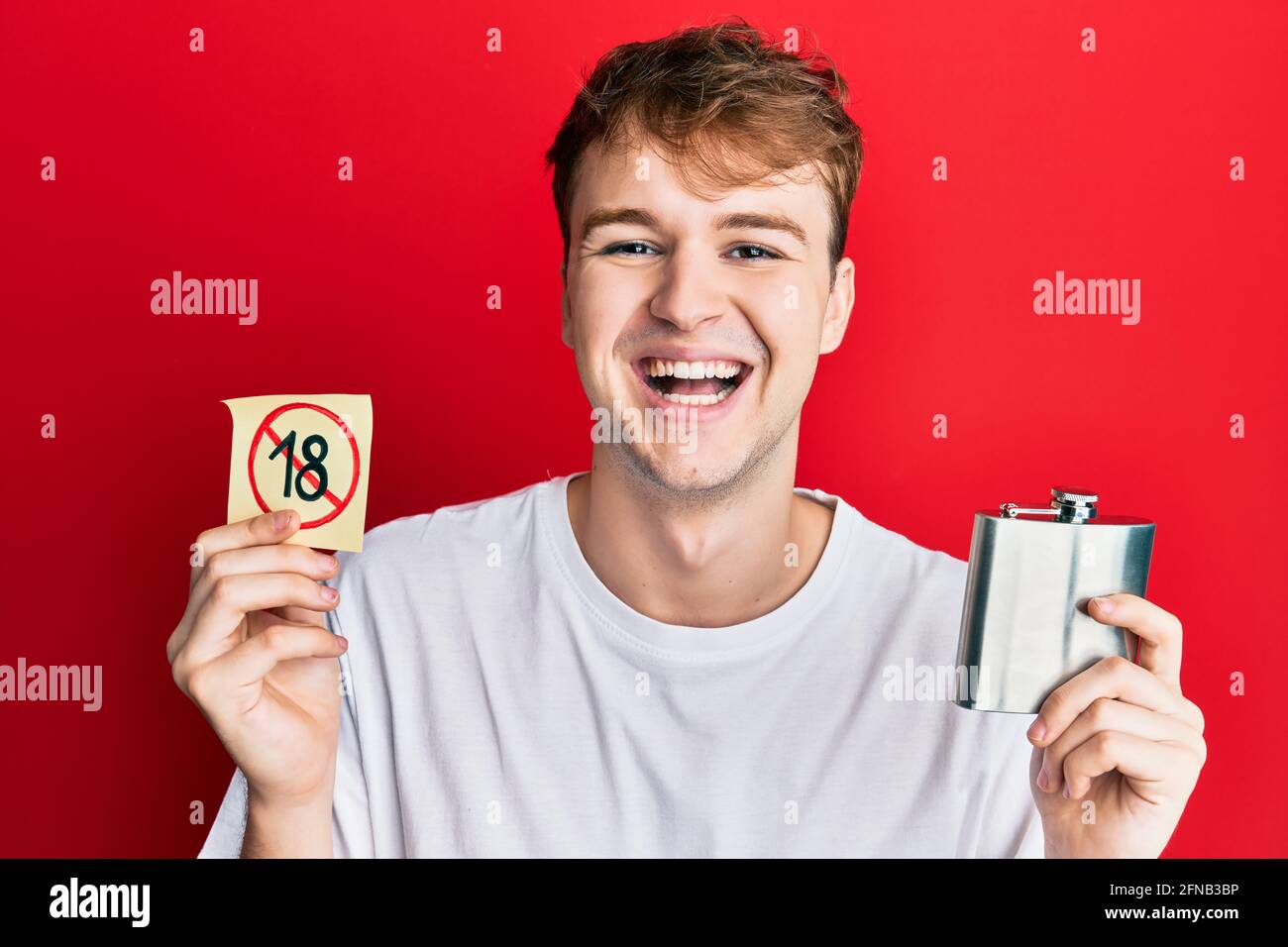 Young caucasian man holding whiskey flask and under 18 forbidden symbol ...