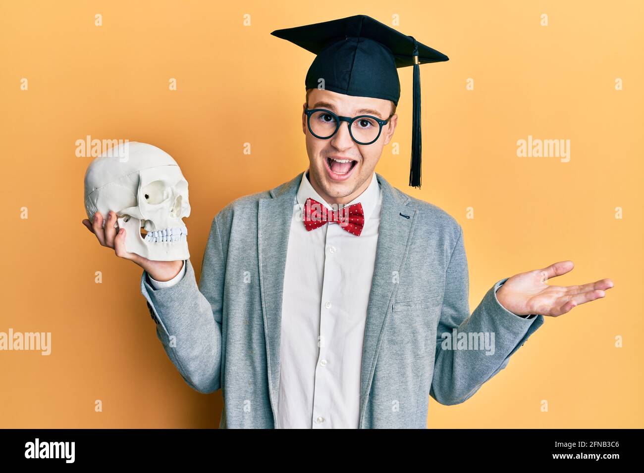 Young caucasian nerd man wearing glasses and graduation cap holding ...